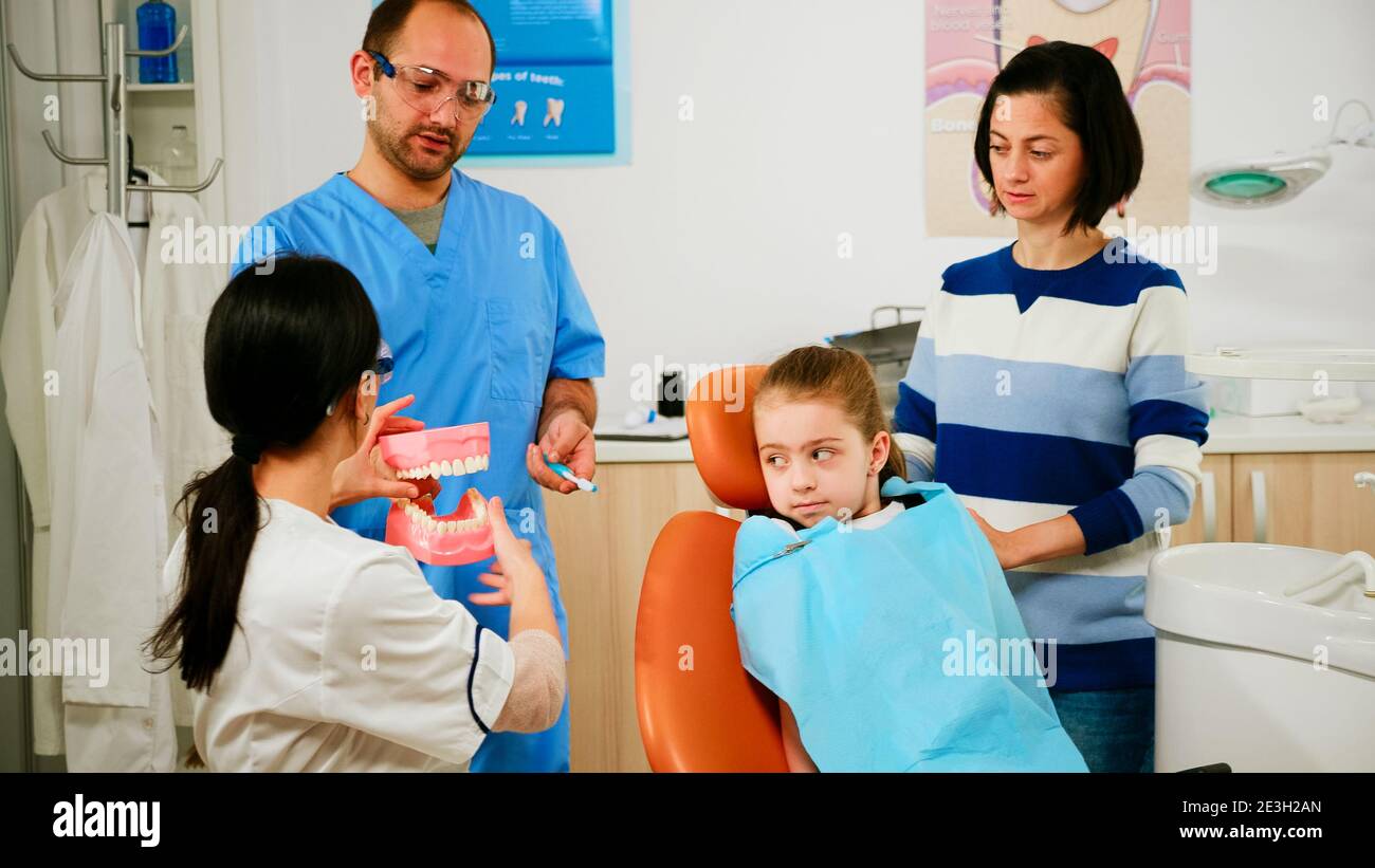 Doctor showing to child the correct dental hygiene using mock-up of ...