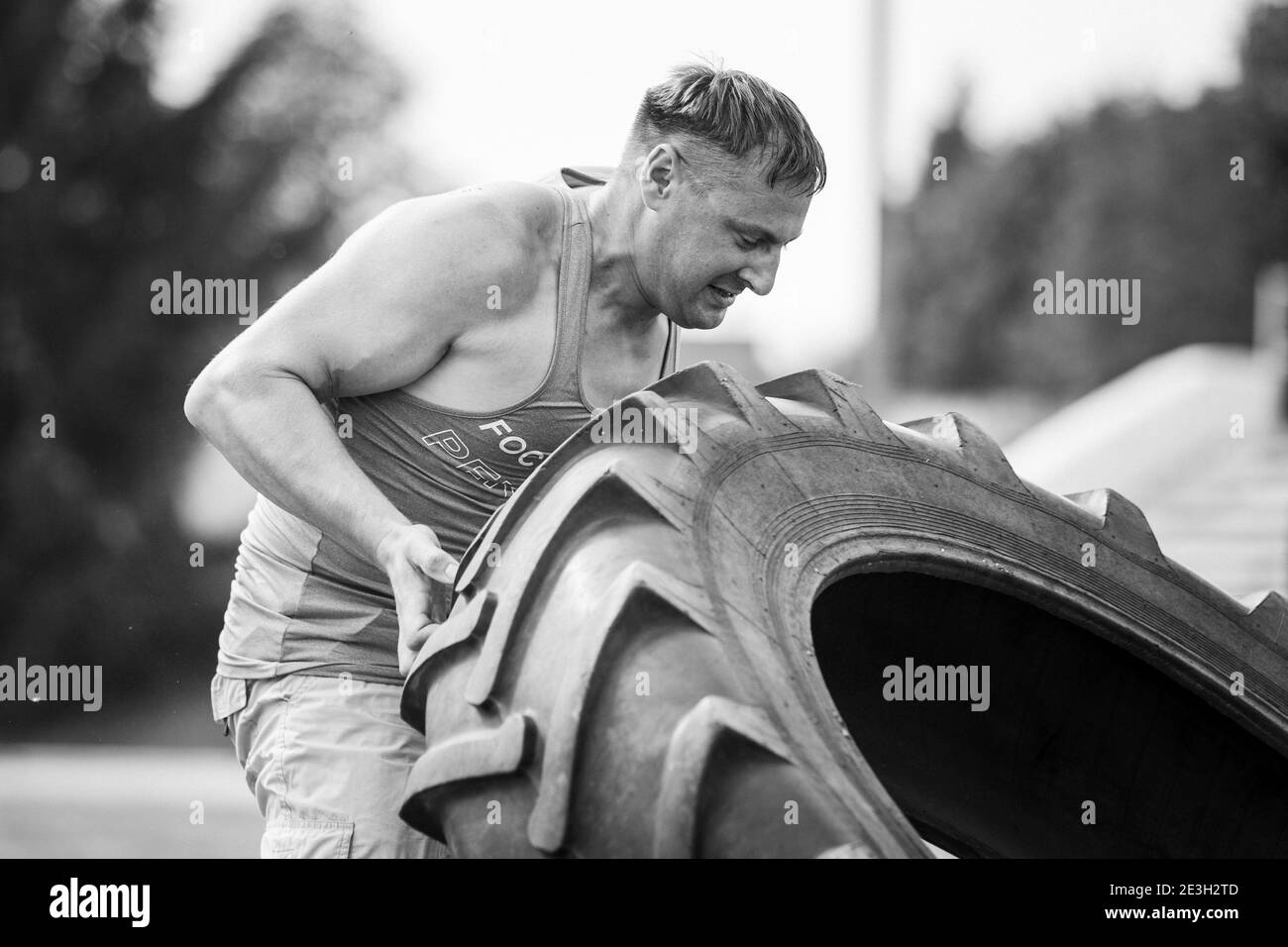 Young man lift up big heavy wheel on competition Stock Photo - Alamy