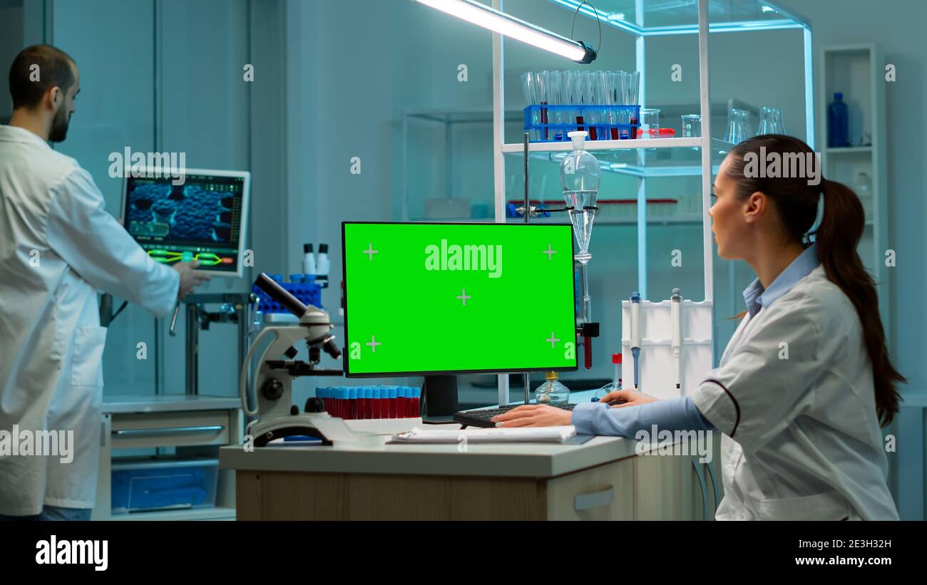 Biochemist sitting at workplace in laboratory using green mock-up ...