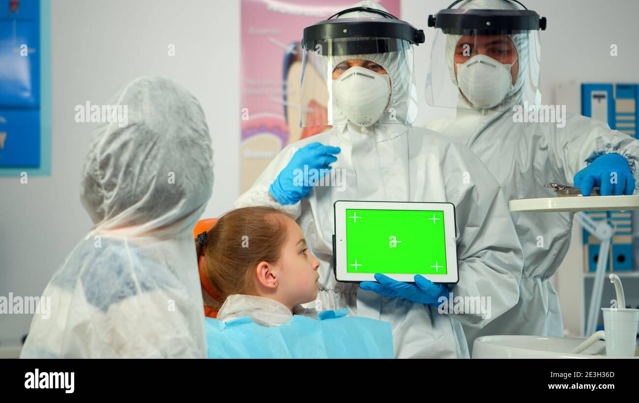 Stomatologist with coverall pointing at mockup greenscreen display ...
