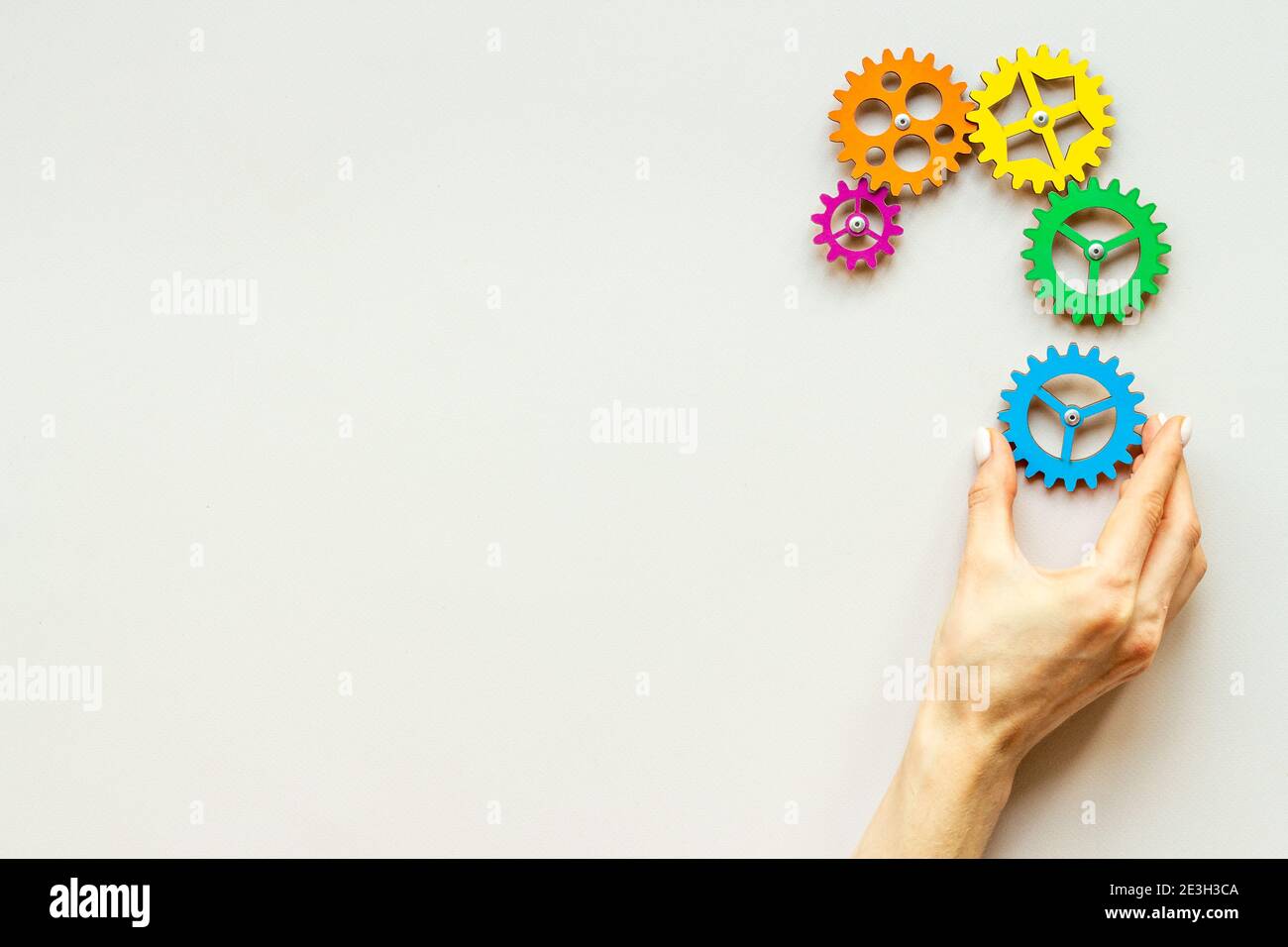 Hand puts a gear into one working mechanism. Teamwork and collaboration ...