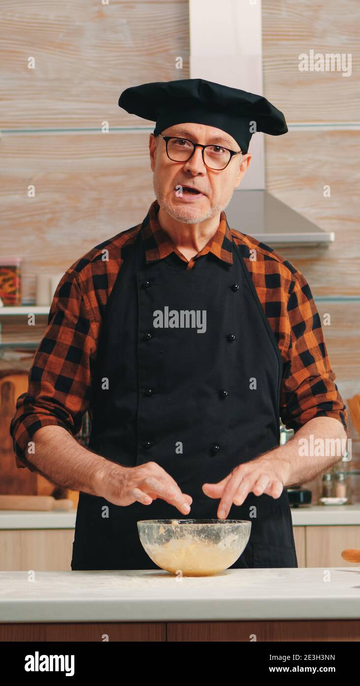 Old man wearing bonete while explaining food preparation recipe looking ...