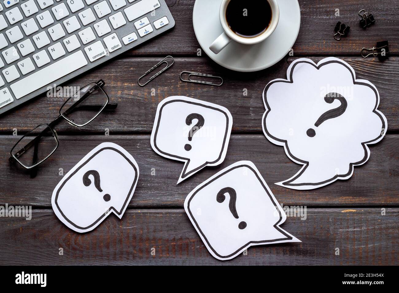 Question marks on office dest - FAQ concept. Top view Stock Photo - Alamy