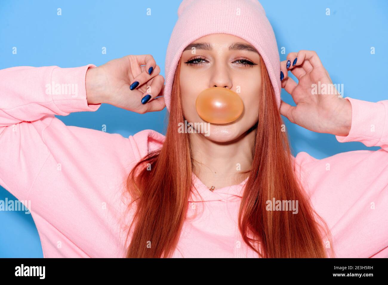 Young Attractive Girl In Pink Clothes Blowing Bubbles From Chewing Gum