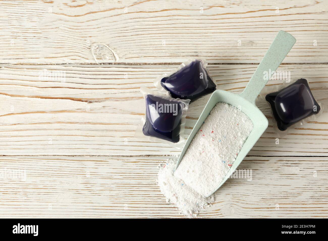 Scoop with washing powder and laundry capsules on white wooden ...