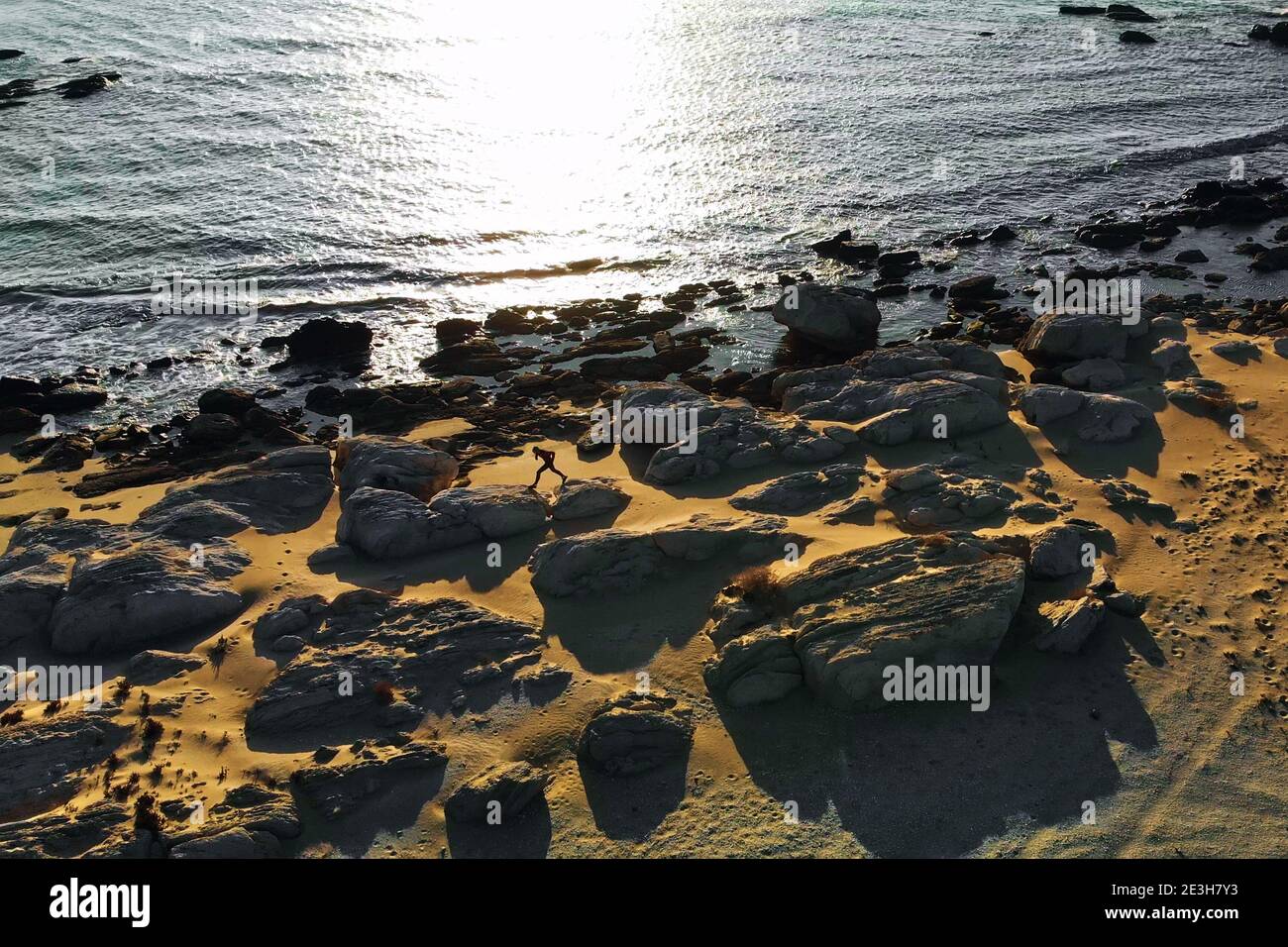 The guy runs along the beach. He jumps from stone to stone. Running ...