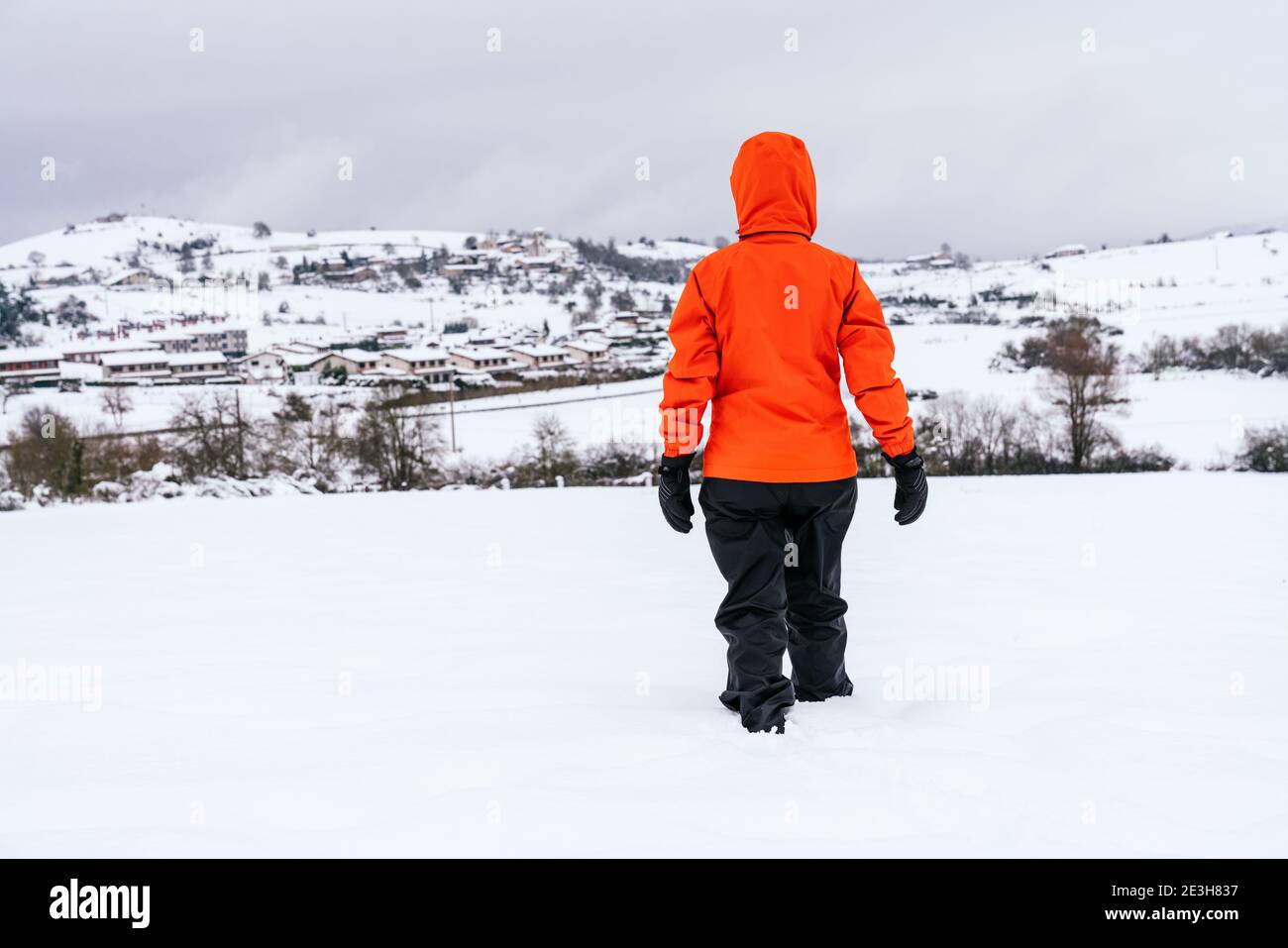 back view of a woman walking in the snow on a mountain with a beautiful ...