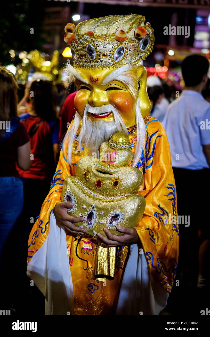 A participant wearing a traditional Chinese mask and costume at a ...