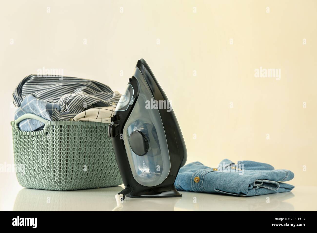 Modern iron and laundry on white table Stock Photo - Alamy
