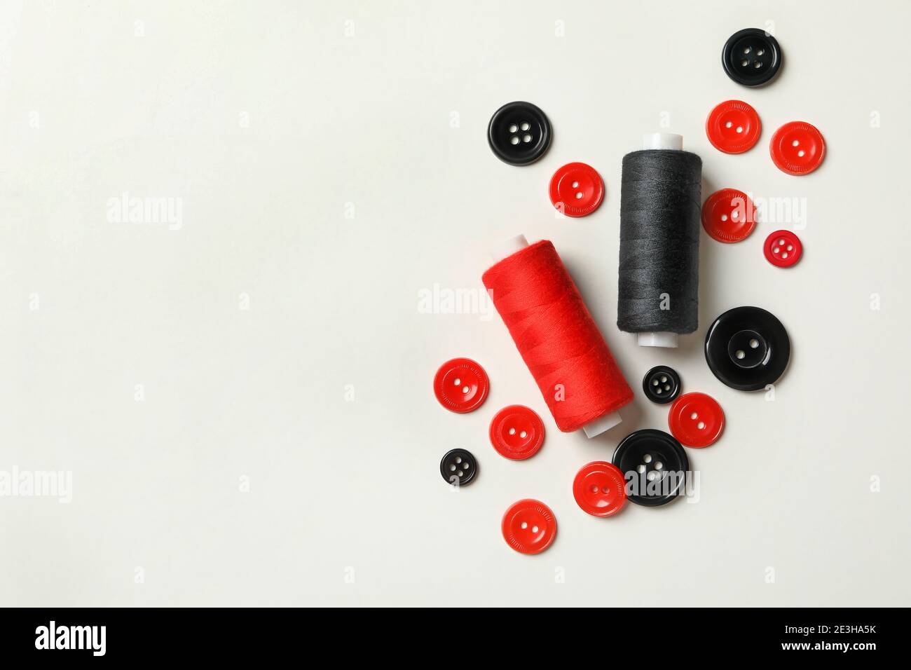 Red and black threads and buttons on white background Stock Photo - Alamy