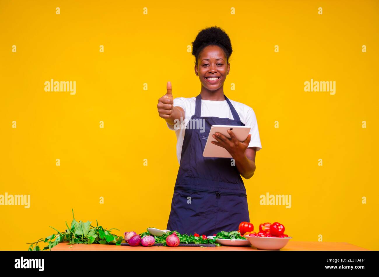 young beautiful nigeria chef smiling as she holding a tablet and did ...