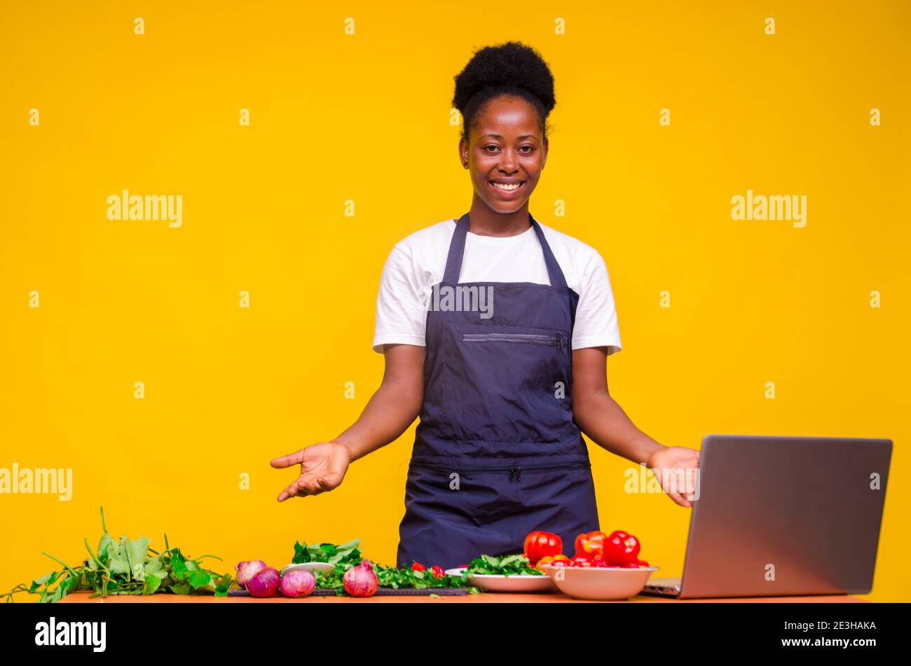 young beautiful african chef isolated over yellow background using her ...