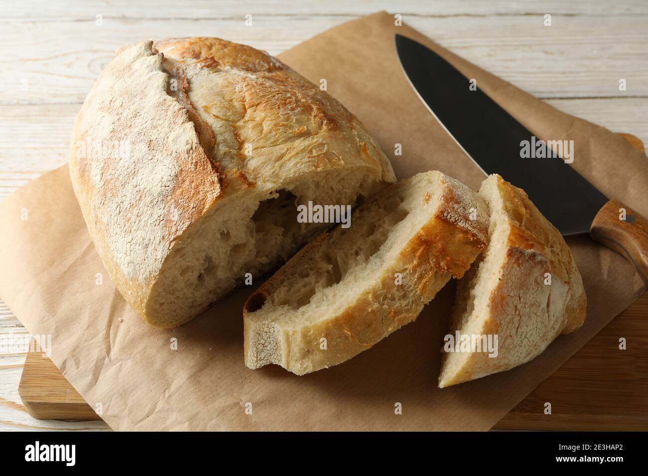 Baking paper with bread and knife on white wooden background Stock ...