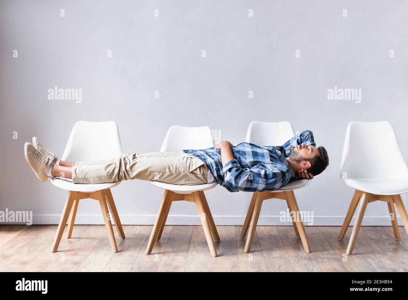 Man in casual wear lying on chairs while waiting in hall Stock Photo ...