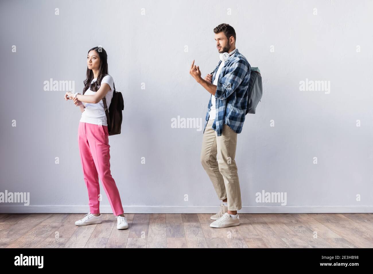 Student showing middle finger near asian woman in hall Stock Photo - Alamy