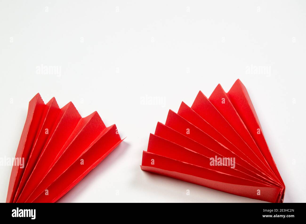 Red origami paper fans, located at the bottom edge on a white ...