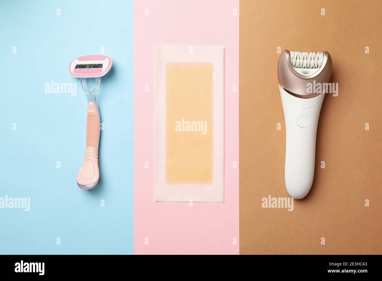 Razor, epilator and wax strip on three tone background Stock Photo - Alamy