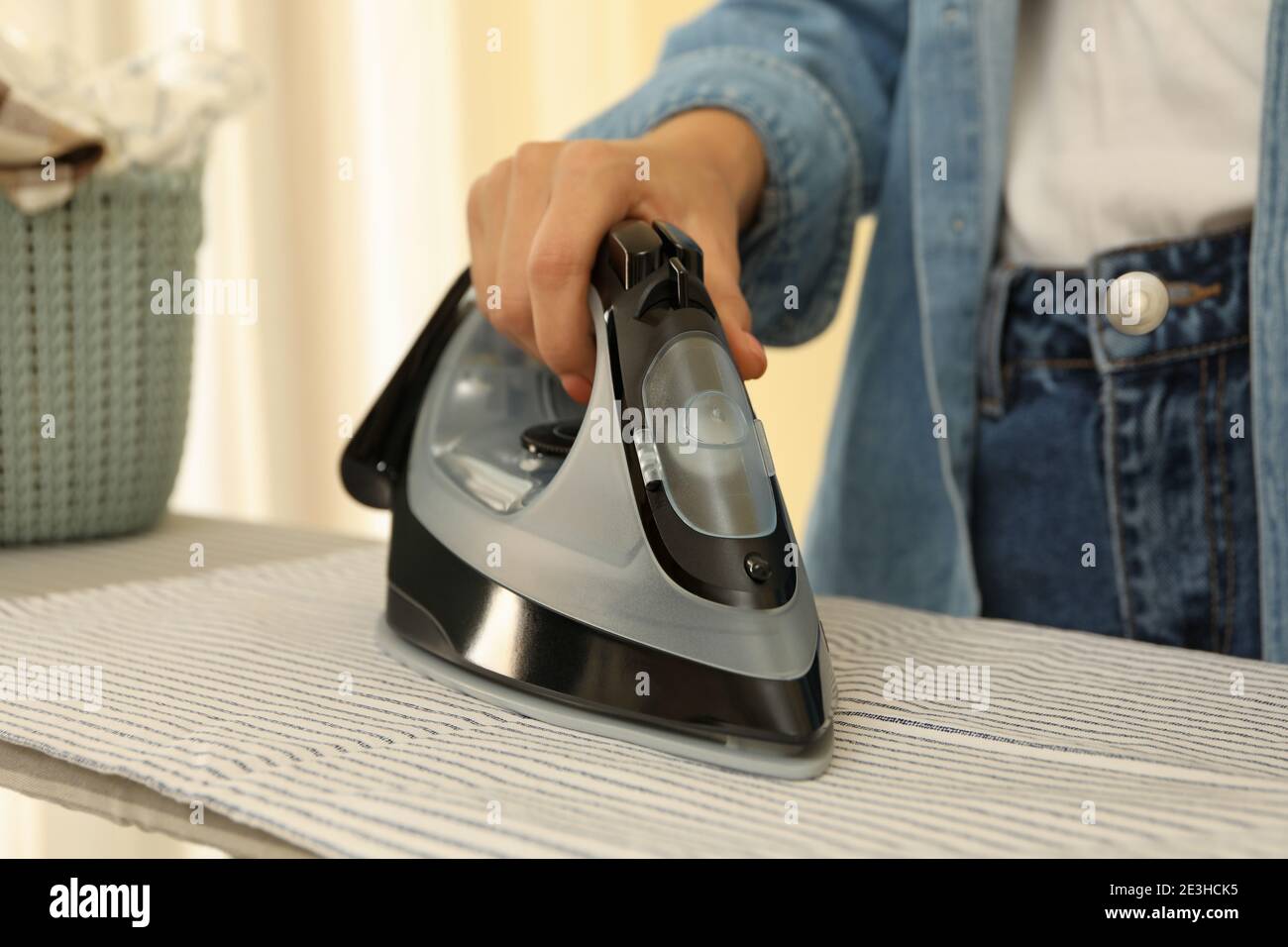 Woman in jeans ironing kitchen towel on ironing board Stock Photo - Alamy