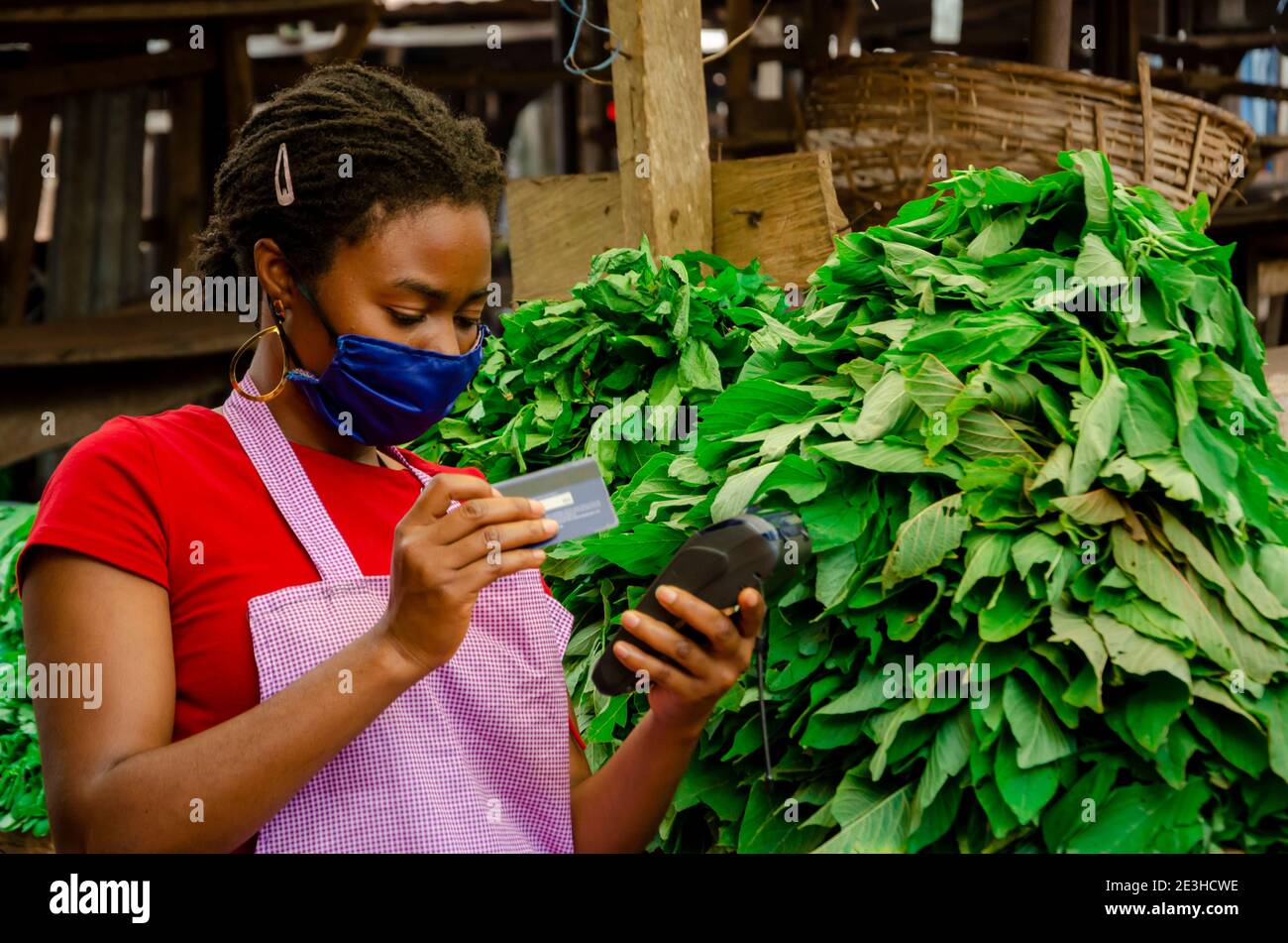 young beautiful african market woman using point of sales machine to ...