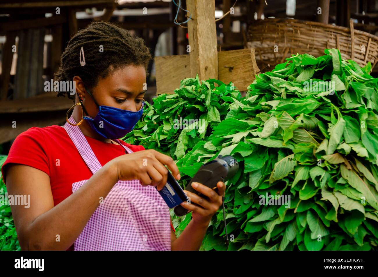 young beautiful african market woman using point of sales machine to ...