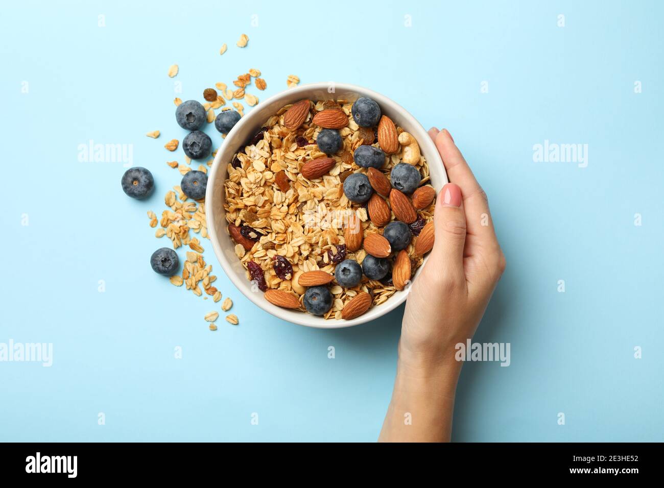 Female hand hold bowl with granola on blue background Stock Photo - Alamy
