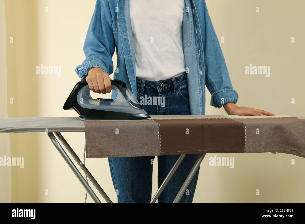 Woman in jeans ironing kitchen towel on ironing board Stock Photo - Alamy