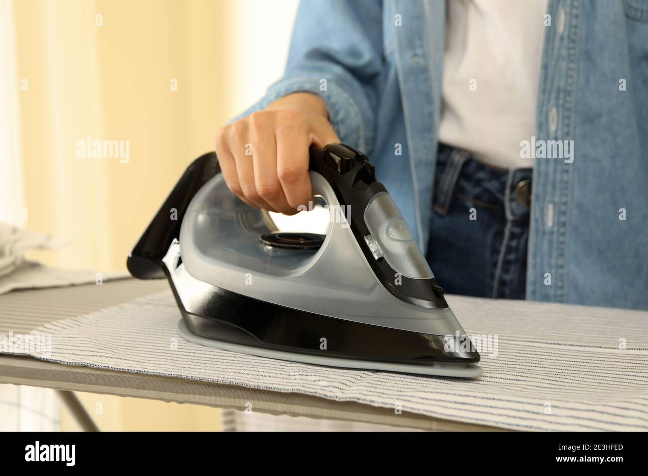 Woman in jeans ironing kitchen towel on ironing board Stock Photo - Alamy