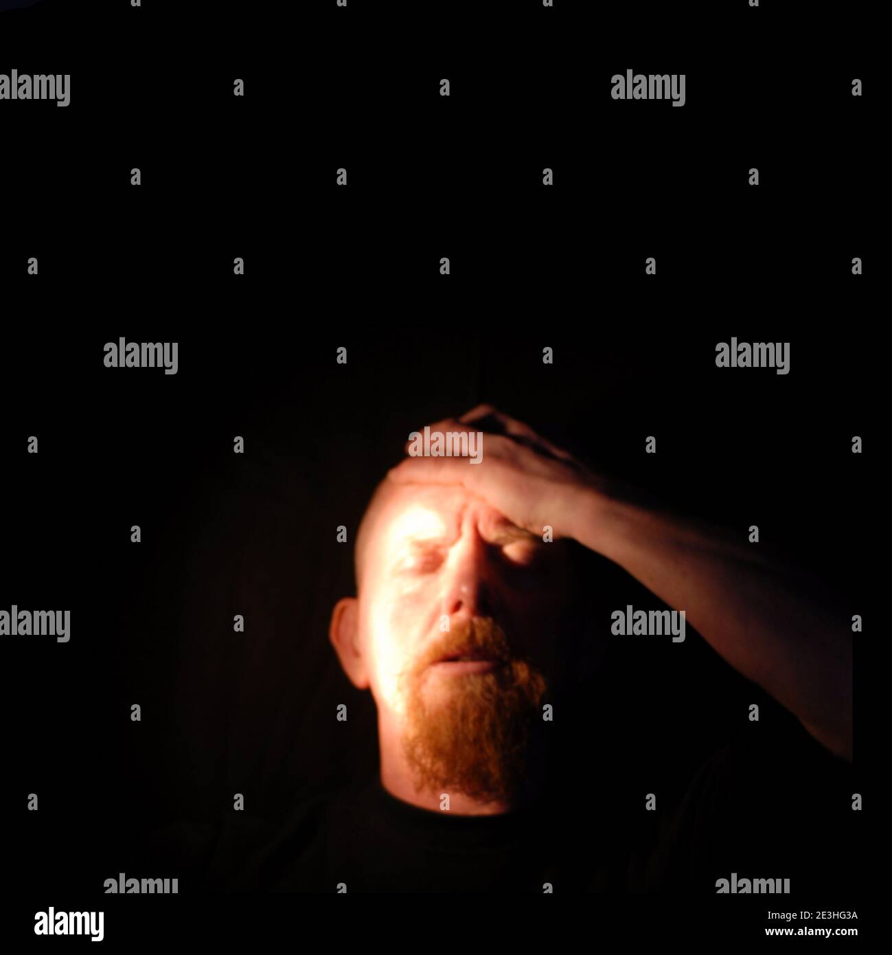 portrait of mans head lit by torchlight against a black background ...