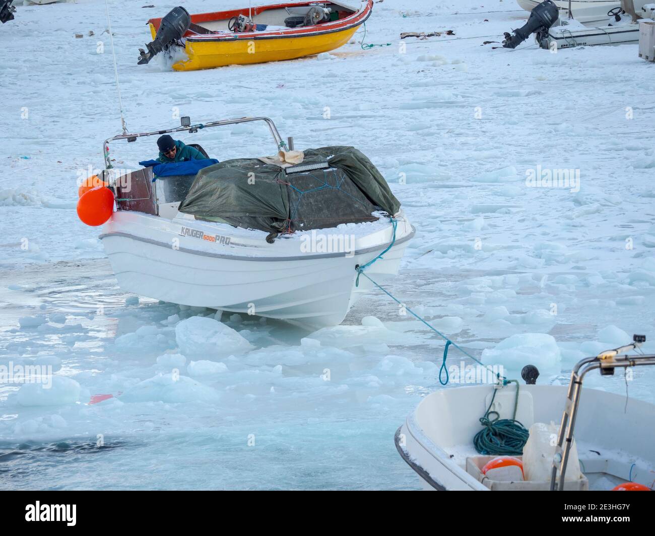 Fishing boat is towed from sea ice to the open water. Winter in the ...
