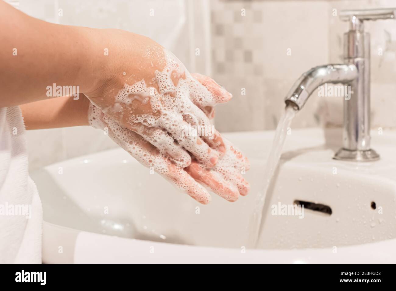 Female washes his hands with soap over a sink in the bathroom. Concept ...