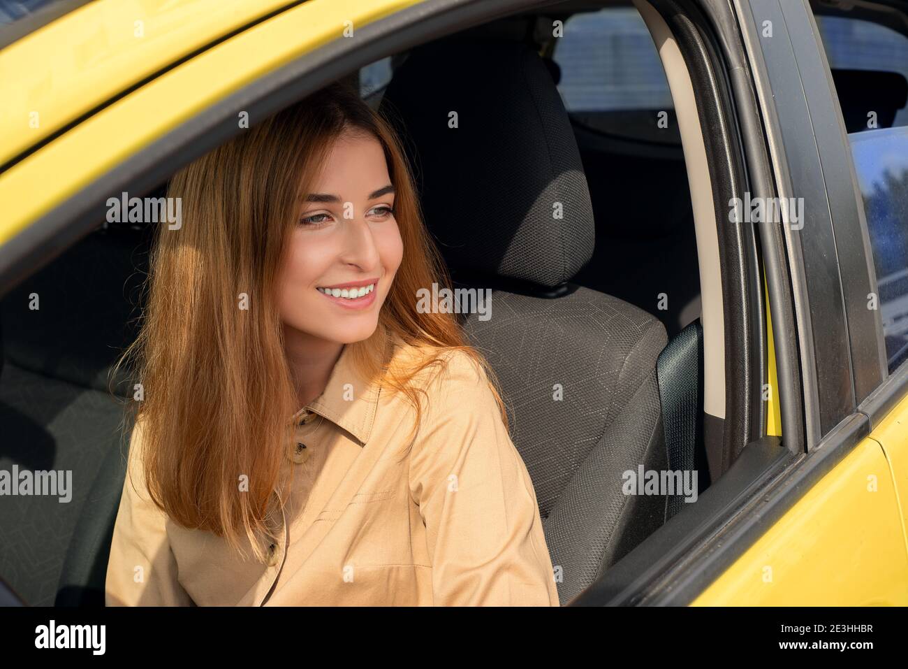 Young female driver looking out the window of her car while sitting on ...