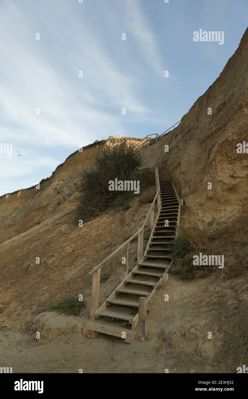 Clay slope with wooden steps against blue sky Stock Photo - Alamy
