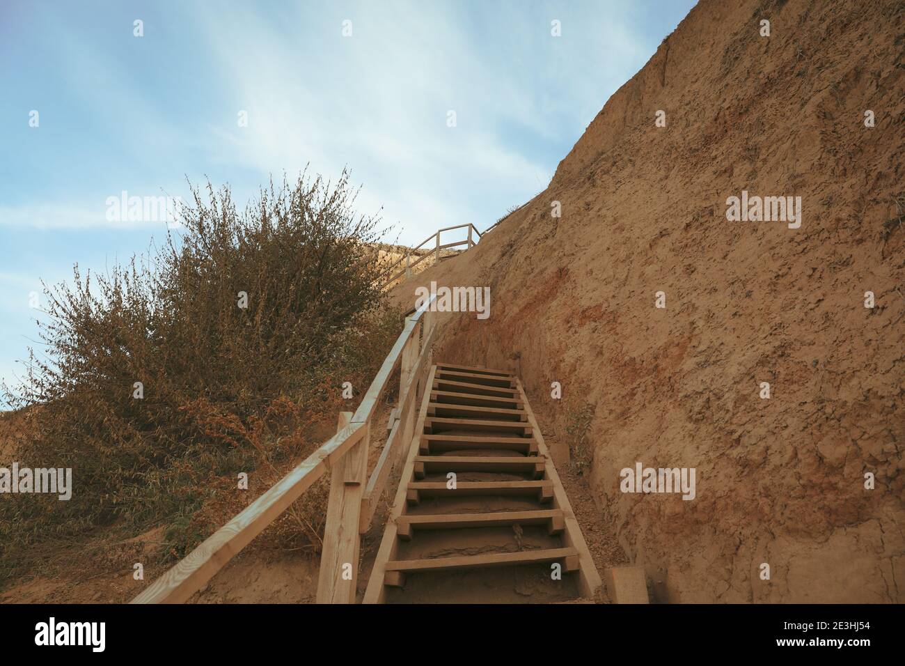 Clay slope with wooden steps against blue sky Stock Photo - Alamy