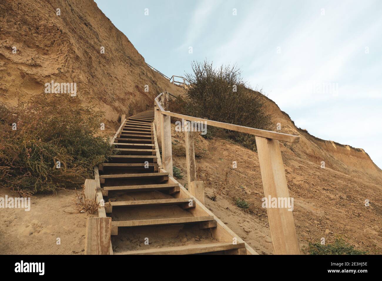 Clay slope with wooden steps against blue sky Stock Photo - Alamy