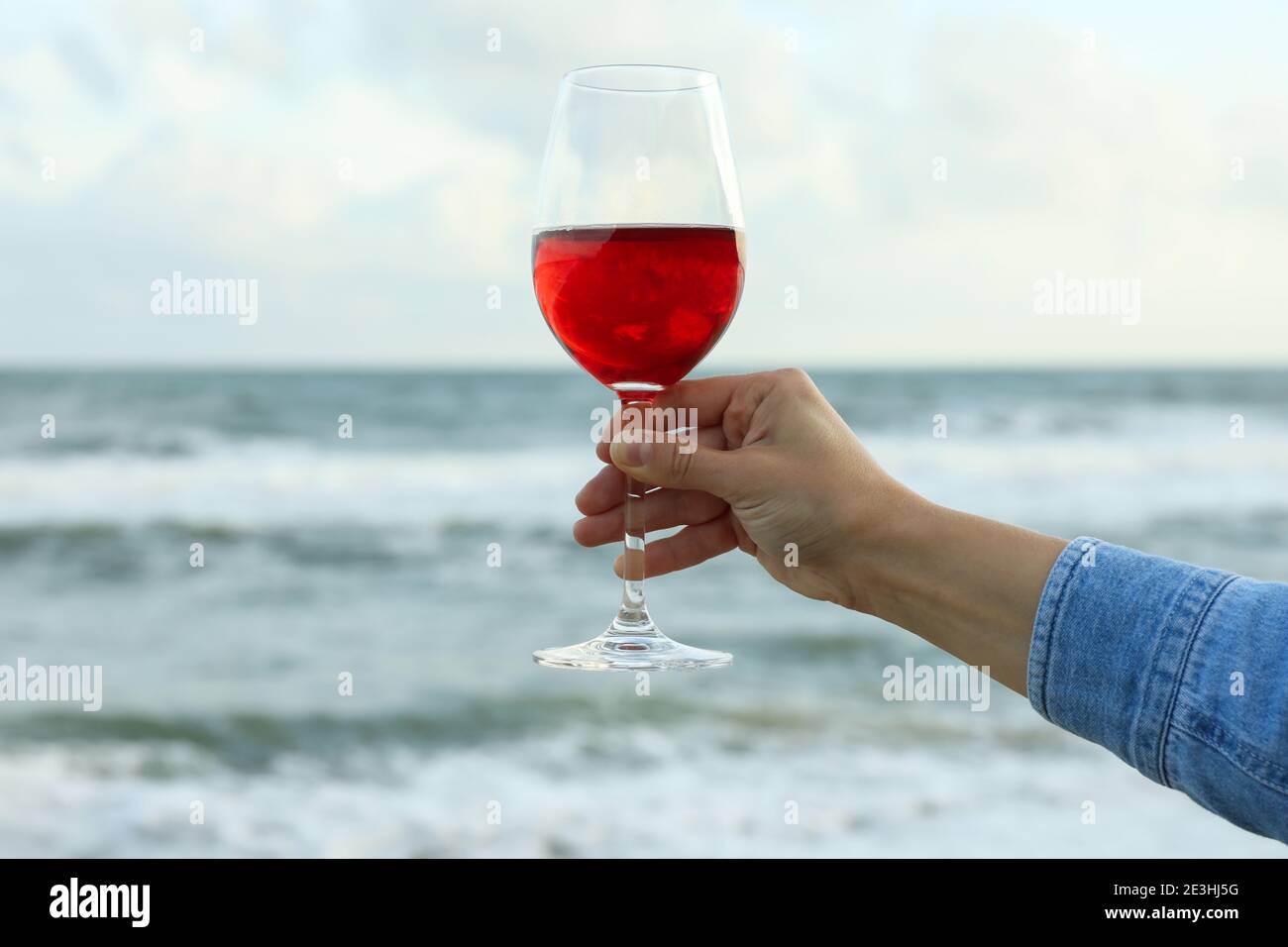 Female hand hold glass of wine against sea Stock Photo - Alamy