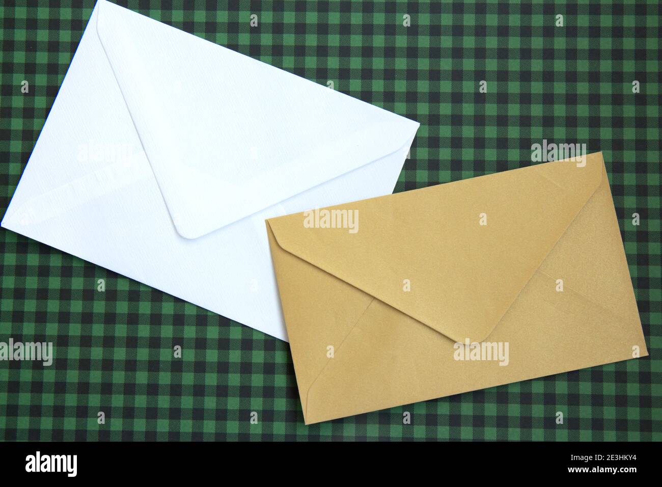 White and beige envelopes and on a green checkered background. Blank ...