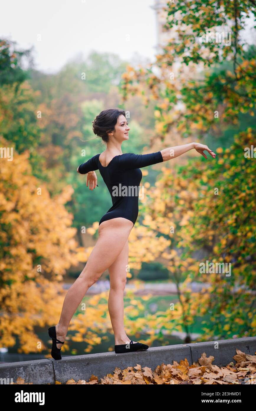 Beautiful female, ballerina, athlete in black bodysuit training in park ...