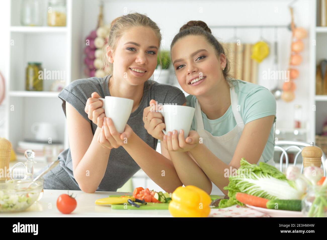 Beautiful teenagers cooking in kitchen and drinking tea Stock Photo - Alamy
