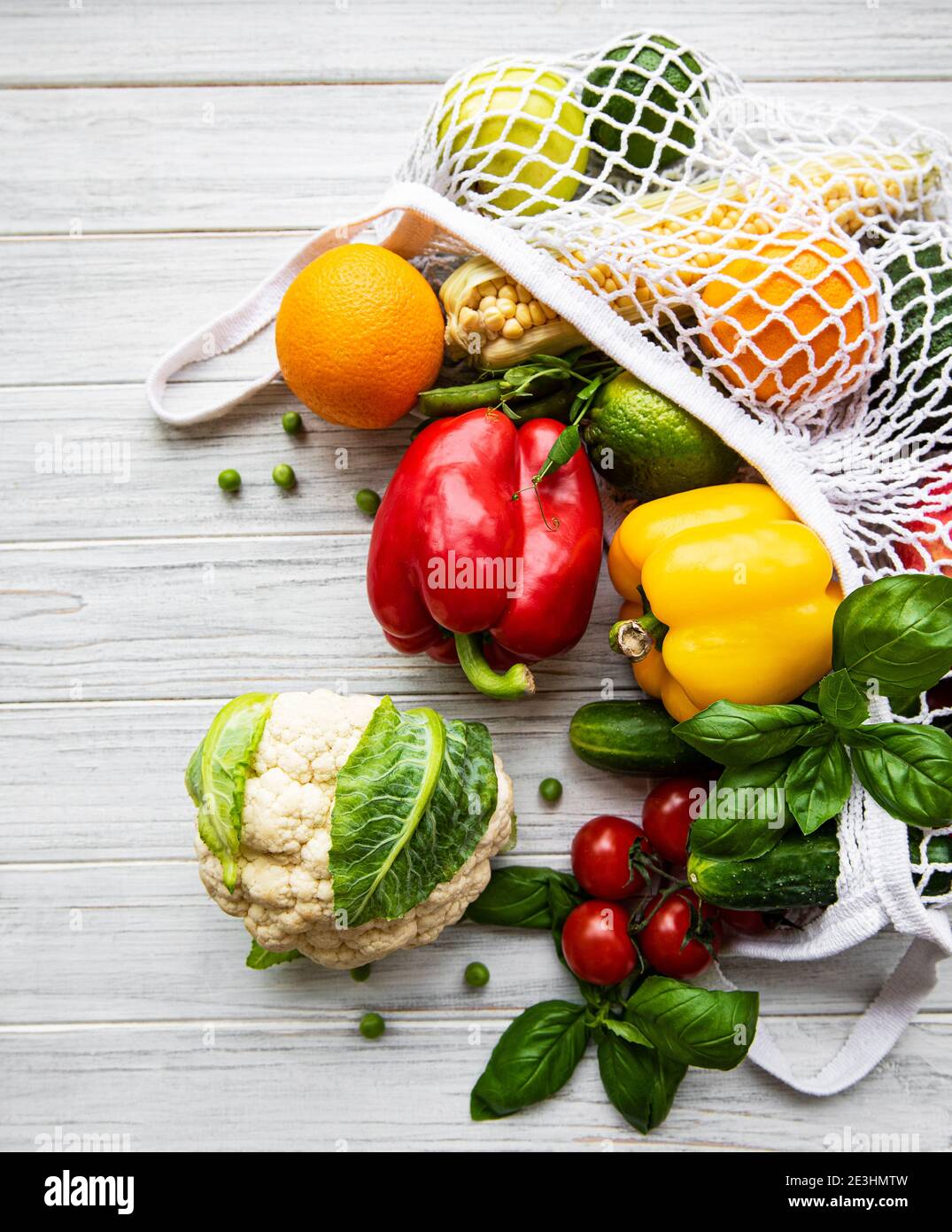 Fresh vegetables and fruits on eco string bag on a white wooden ...