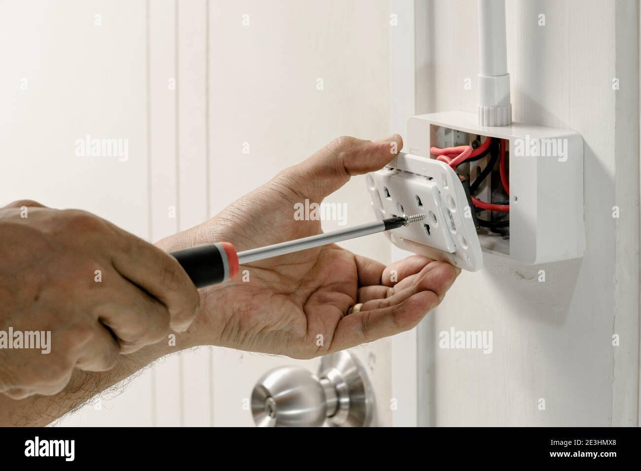 The electrician is using a screwdriver to attach the power cord to the ...