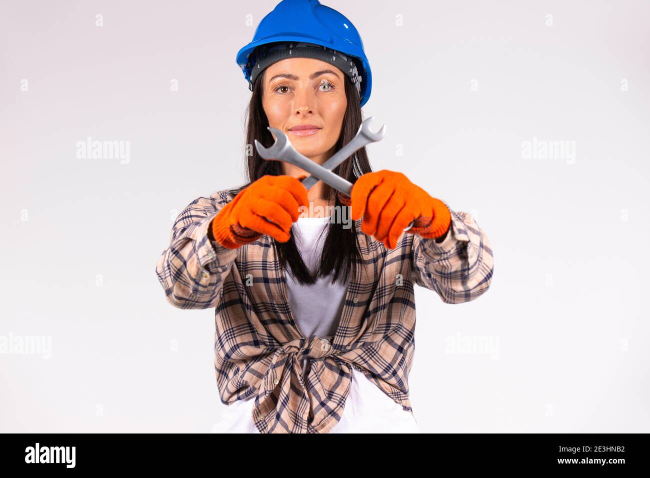 Young mechanic in a hard hat poses with tools on a white background and ...