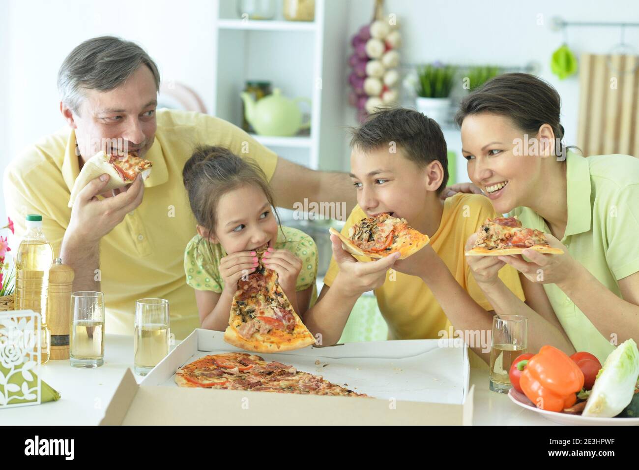 Portrait of happy family eating pizza together Stock Photo - Alamy