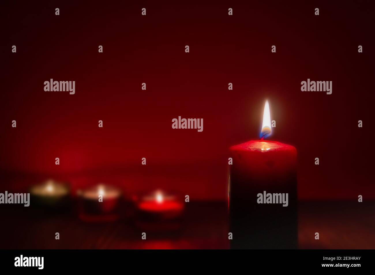 Red candle burning in dark with focus on single candle in foreground ...