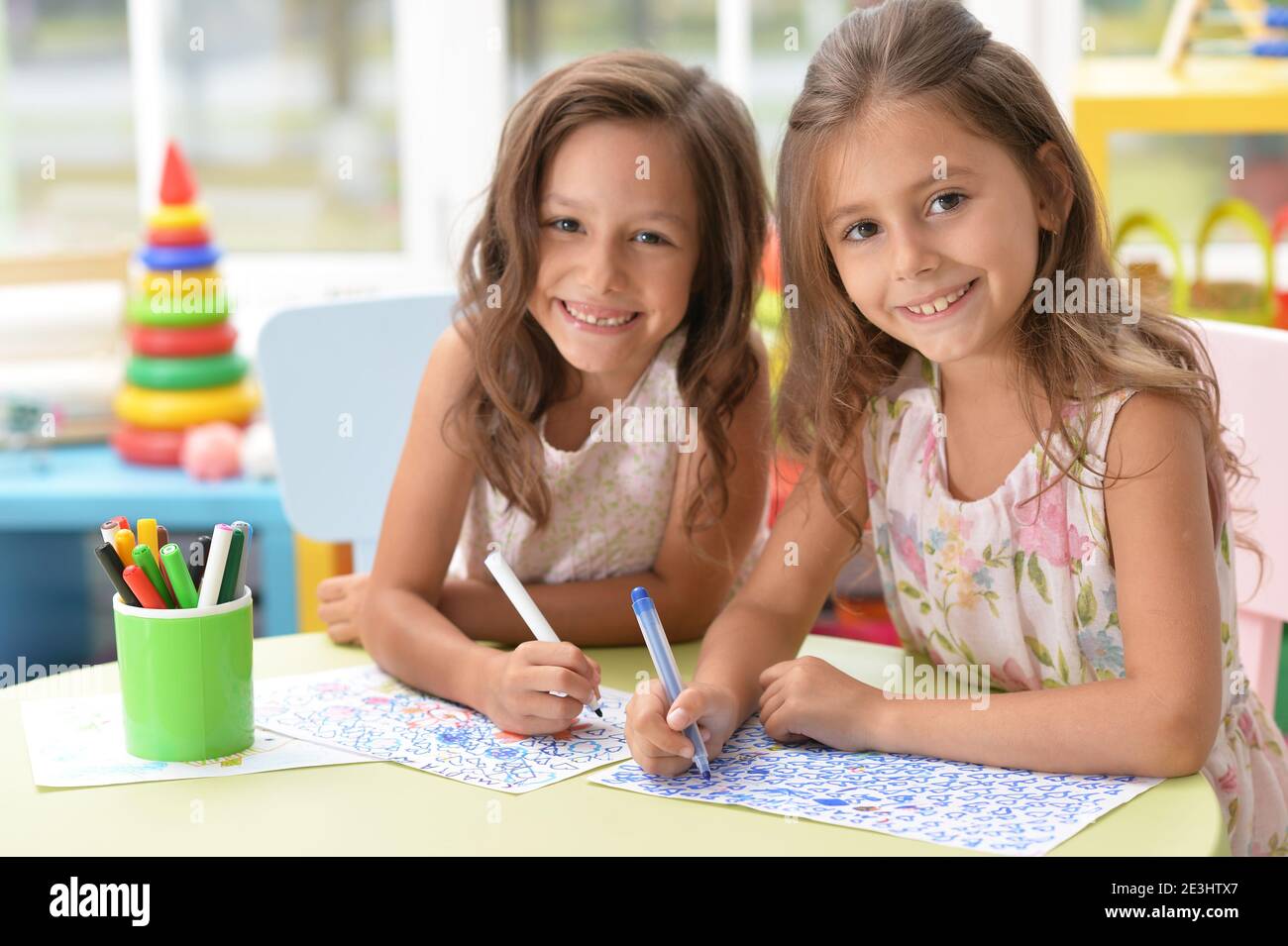 Two cute little girls drawing with pencils Stock Photo - Alamy