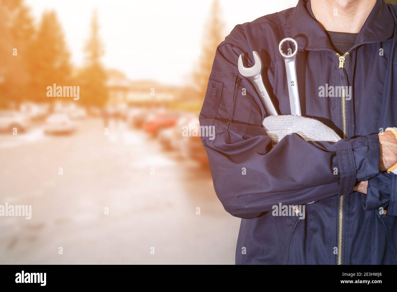 Car repairman wearing a dark blue uniform standing and holding a wrench ...