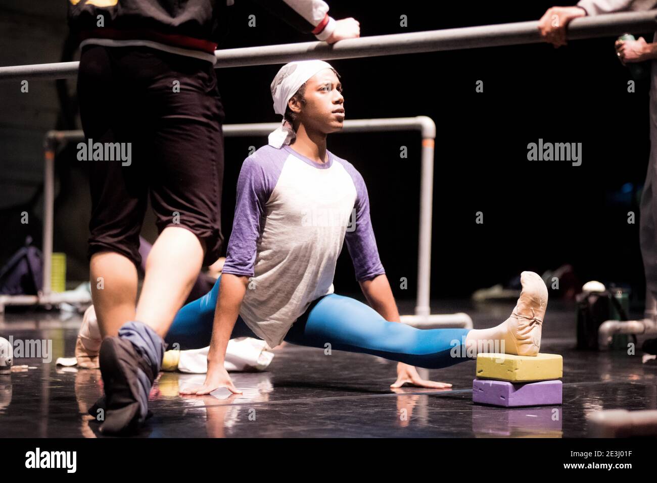 Black male ballet dancer warms up on the floor before a ballet class ...