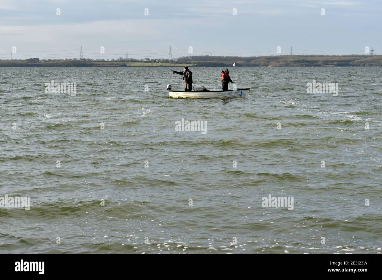 Two men fly fishing from a small boat on Anglian Waters Grafham Water ...