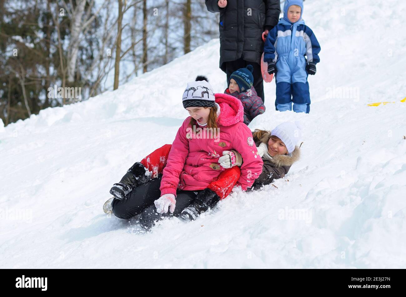 Belly slide down ice slide. Two laughing little girls going down the ...