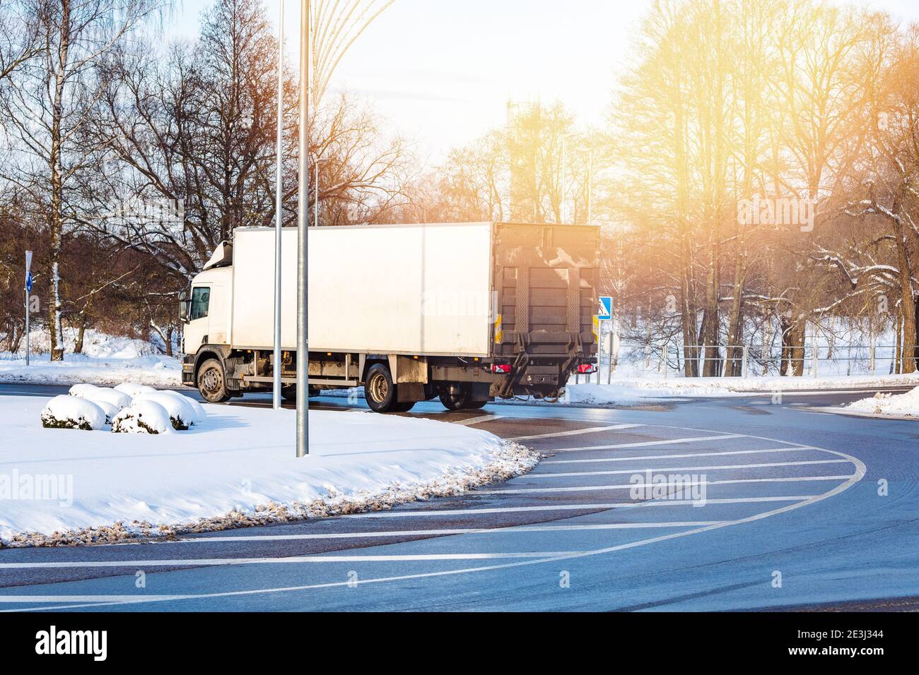 White delivery lorry maneuvering in the narrow pass of a landscaped ...