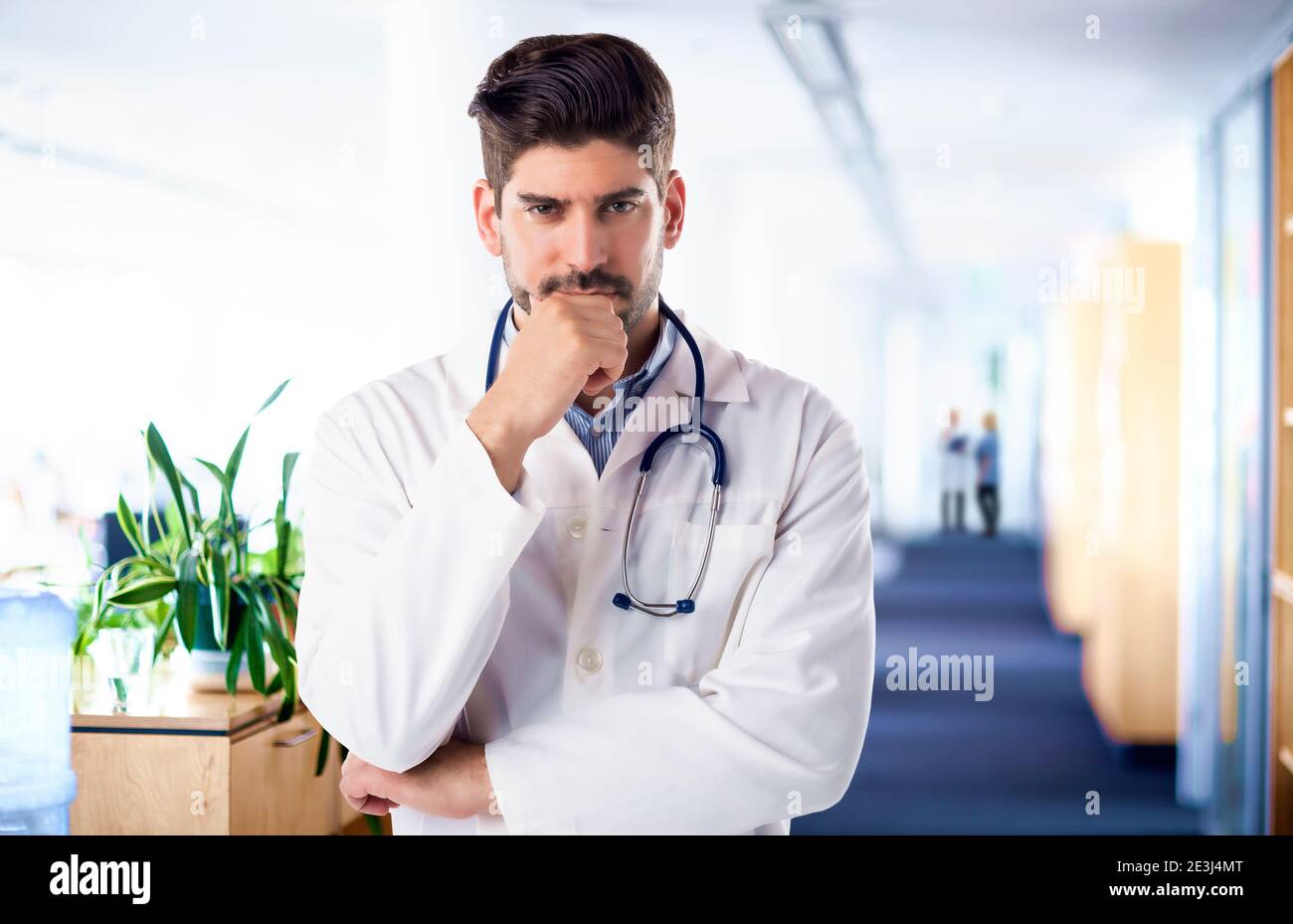 Portrait of thinking male doctor standing on hospital’s foyer Stock ...